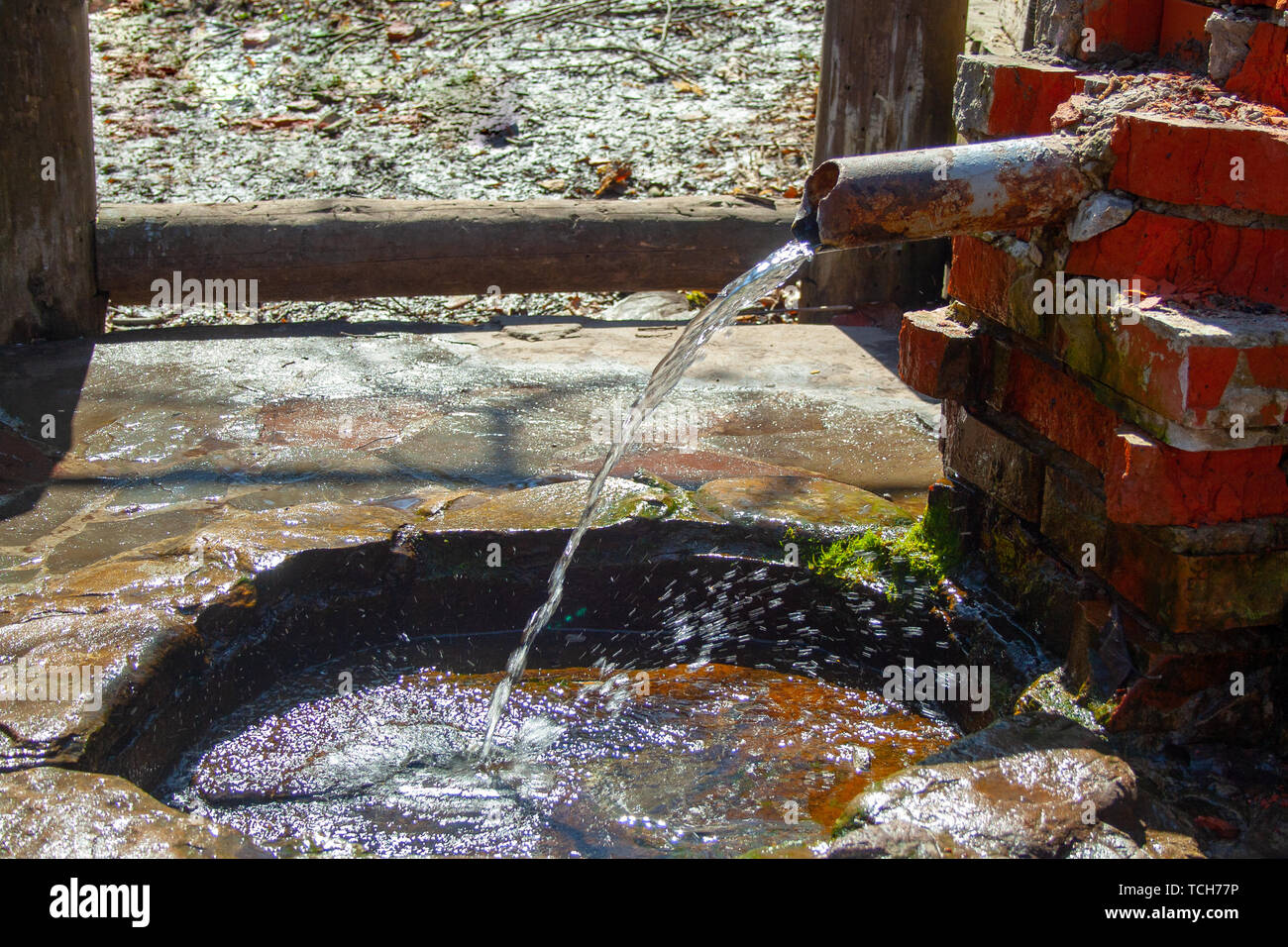 Natural spring folded of old bricks and metallic pipe. Clean fresh ...