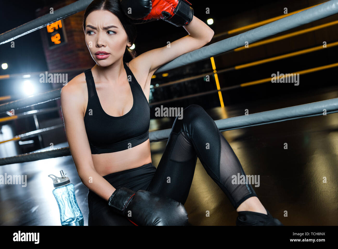 upset woman in boxing gloves sitting in sports center Stock Photo - Alamy