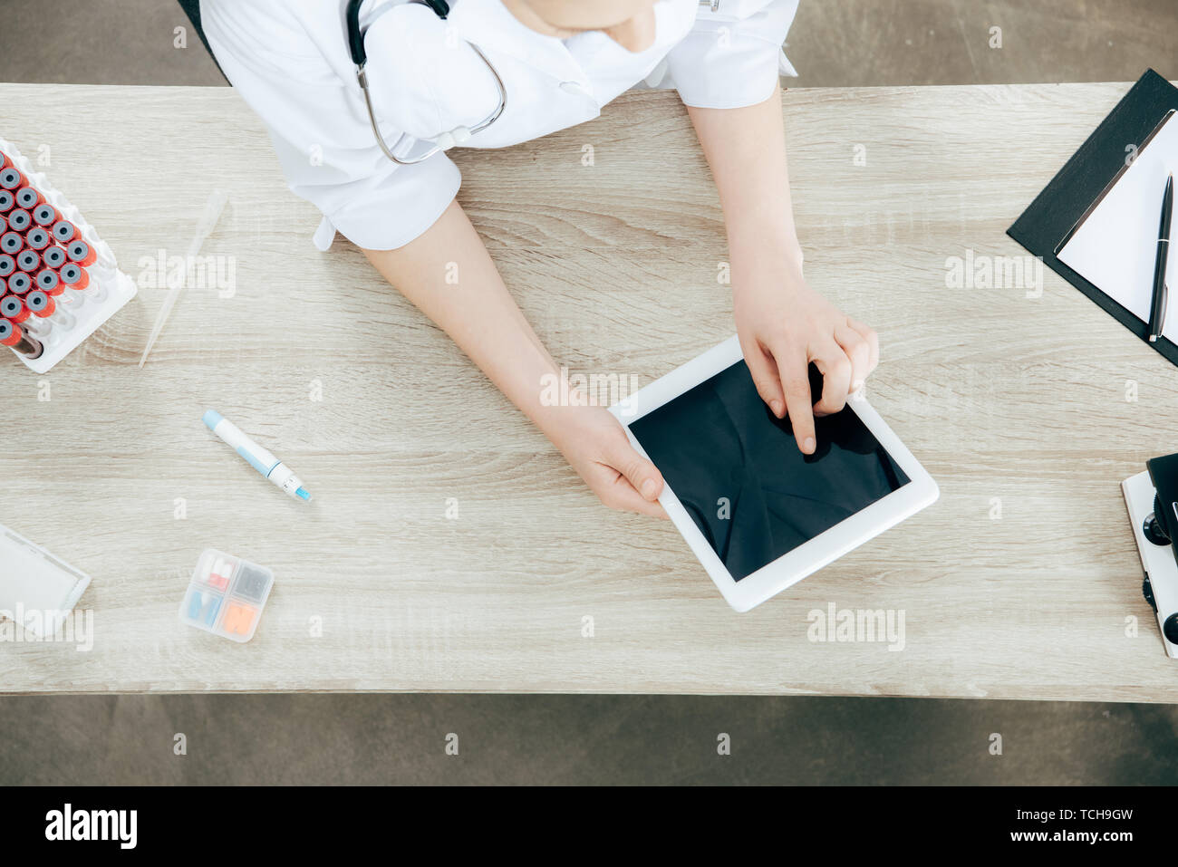 overhead view of doctor in white coat using digital tablet with blank ...