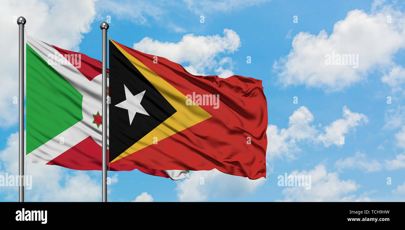Burundi and East Timor flag waving in the wind against white cloudy ...