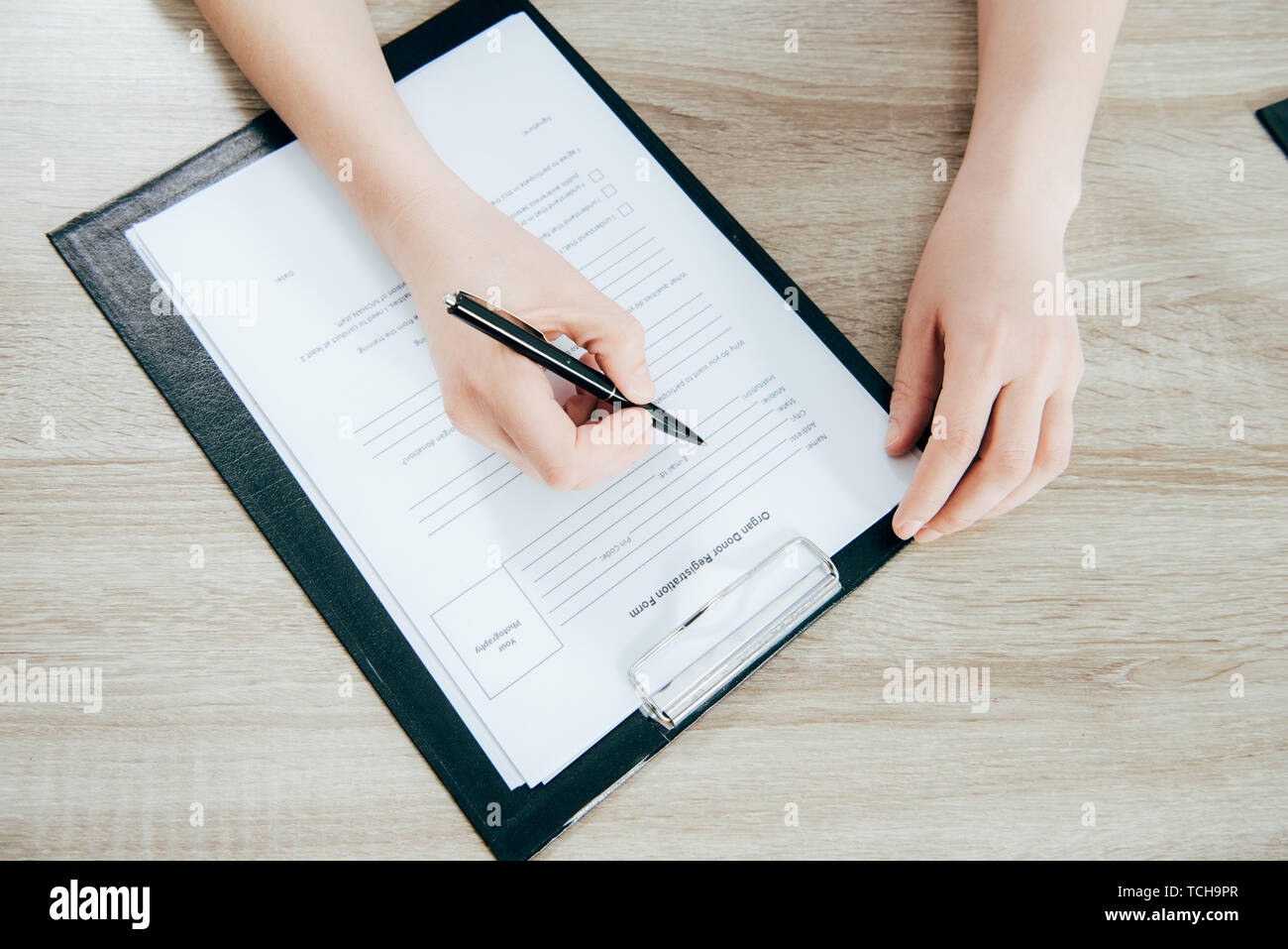 cropped view of donor signing registration form on wooden surface Stock ...