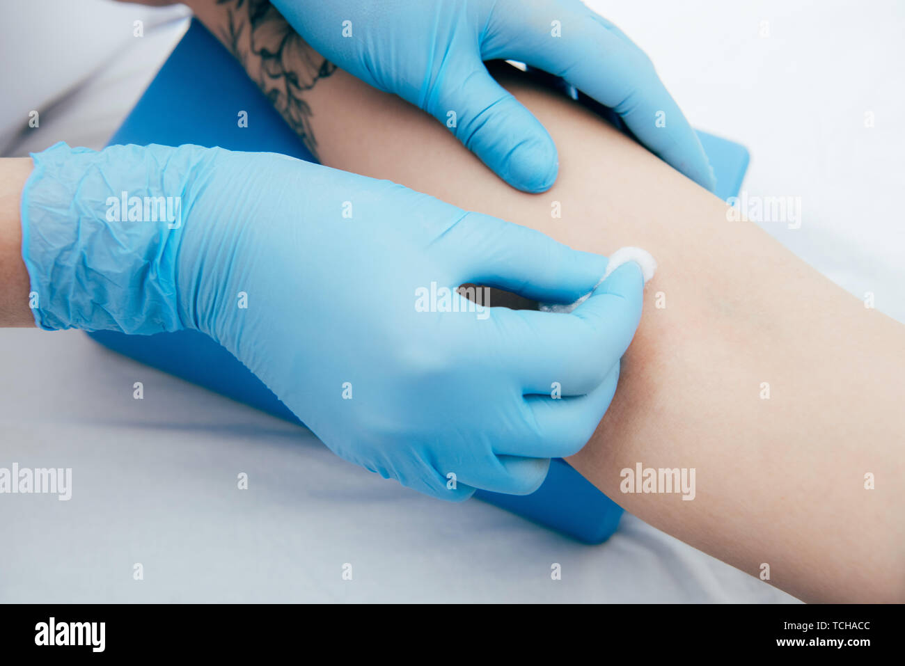 partial view of doctor in latex gloves preparing patient for injection ...