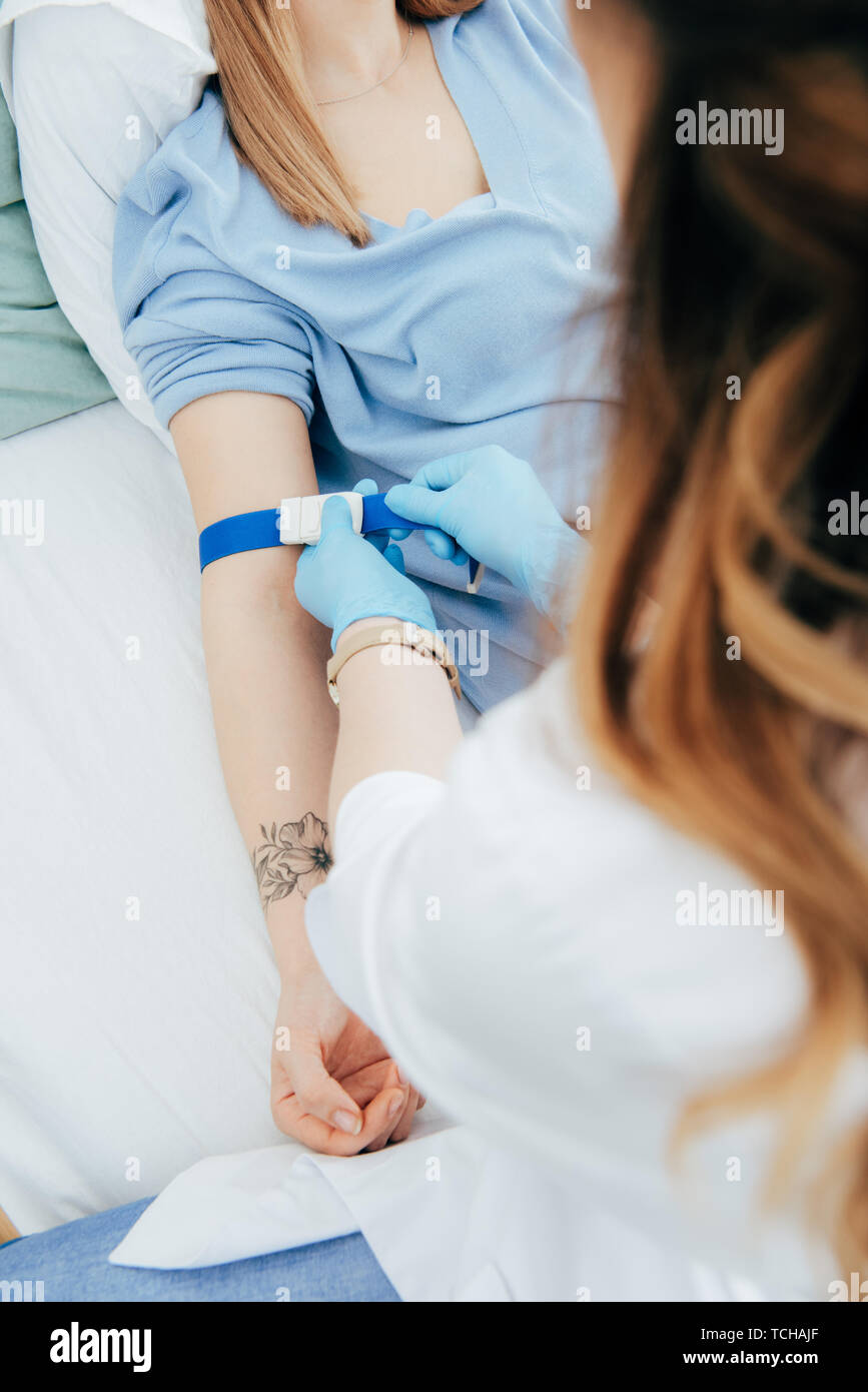 partial view of doctor using tourniquet for blood test in hospital ...