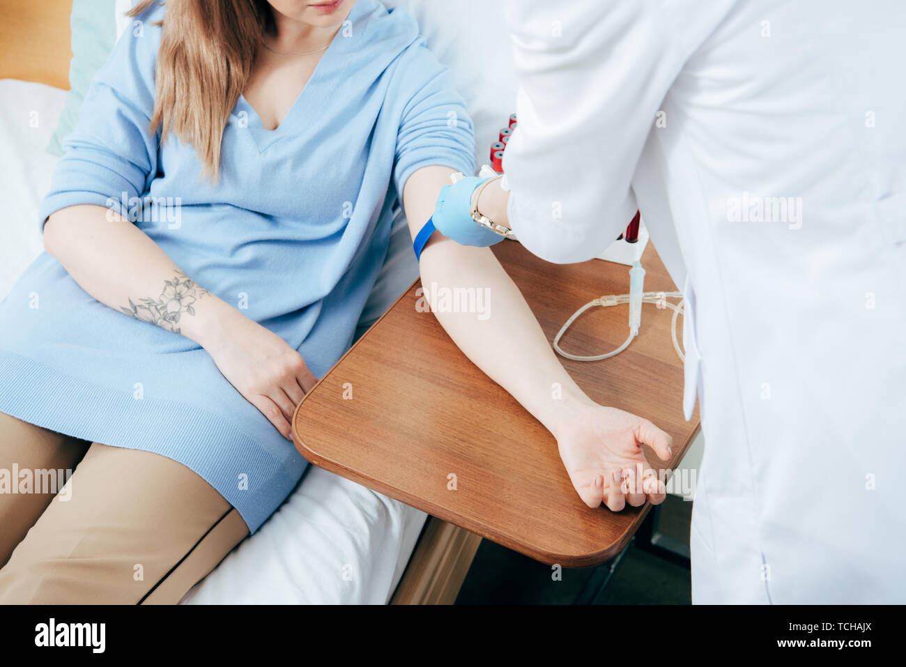 partial view of doctor using tourniquet for blood test in hospital ...