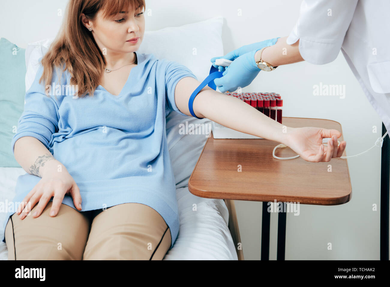 partial view of doctor using tourniquet for blood test in hospital ...