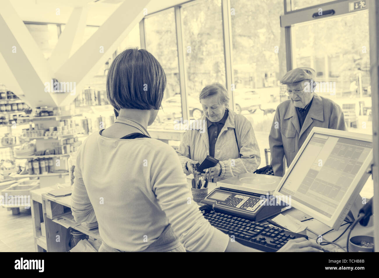 Elderly couple at cashier desk paying to teller in local zero waste ...