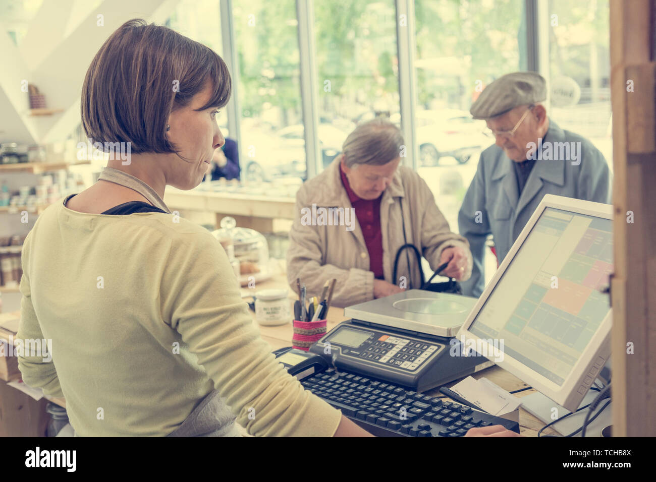 Elderly couple at cashier desk paying to teller in local zero waste ...