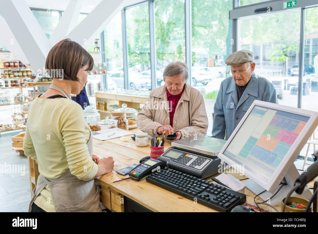 Elderly couple at cashier desk paying to teller in local zero waste ...