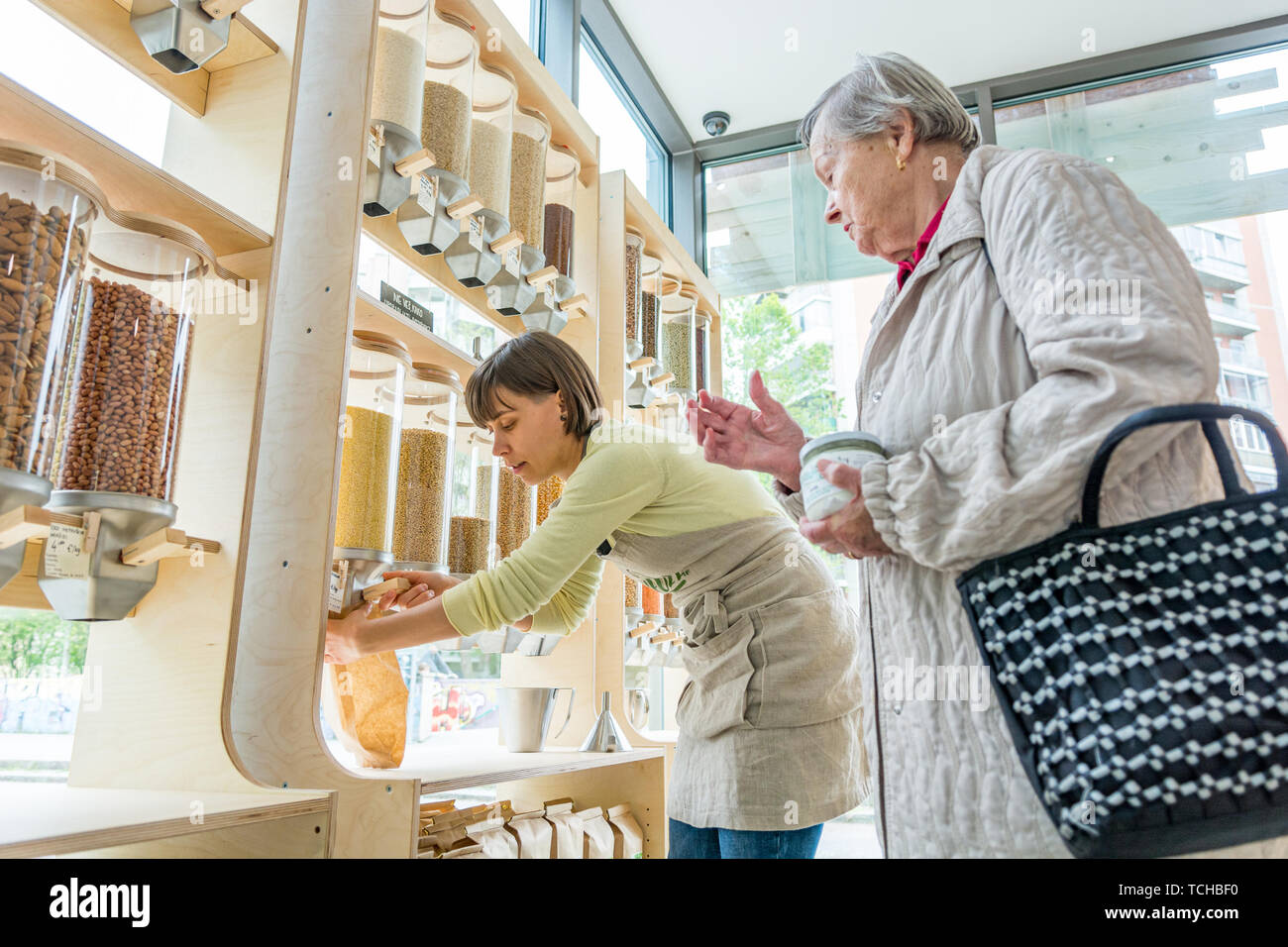 Young female shopkeeper helping elderly lady in zero waste store ...