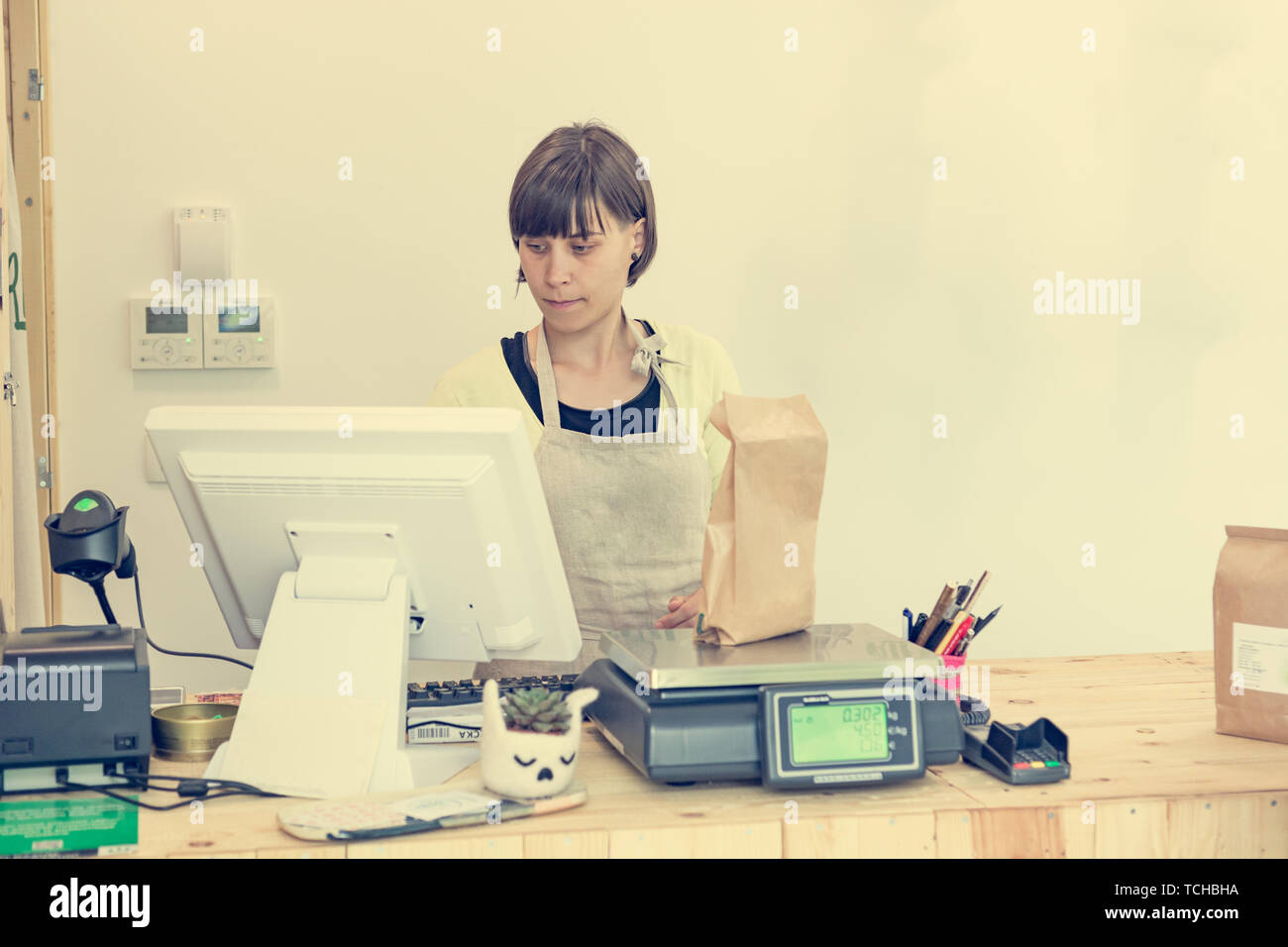 Young female shopkeeper at cash desk weighing food. entrepreneur ...