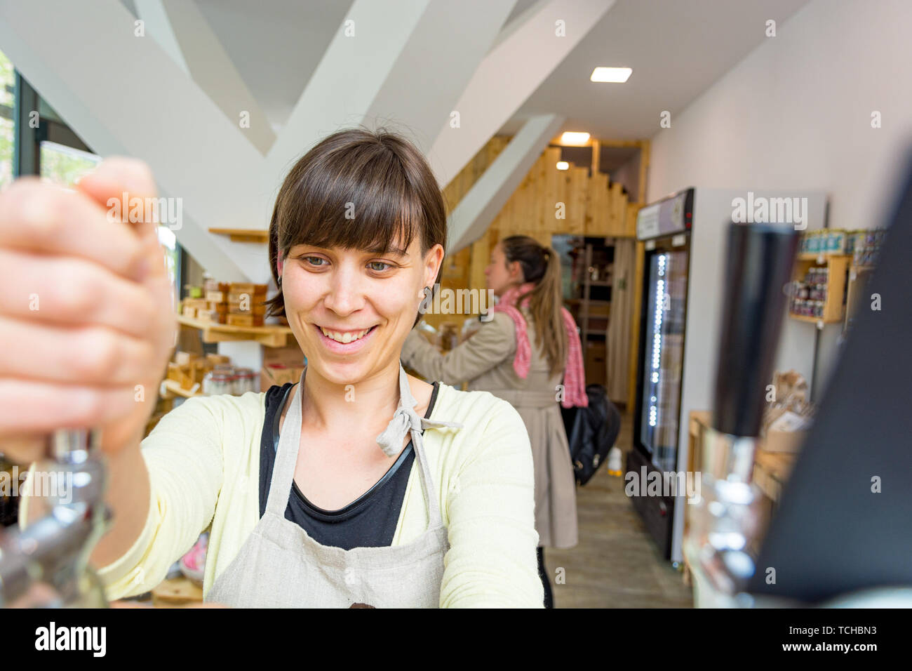 Young shopkeeper pouring delicious organic juice into glass bottle at ...