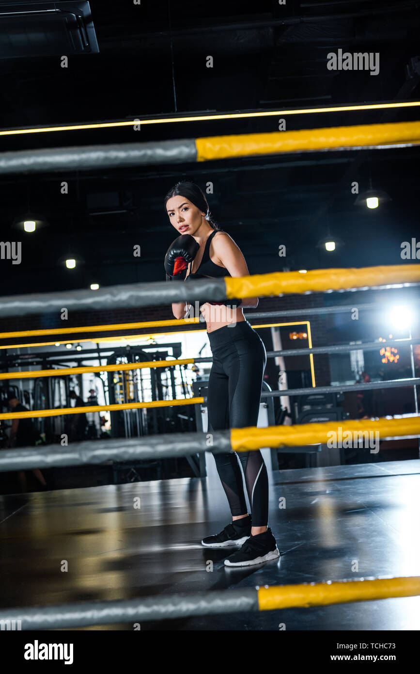 selective focus of attractive woman boxing while standing in boxing ...