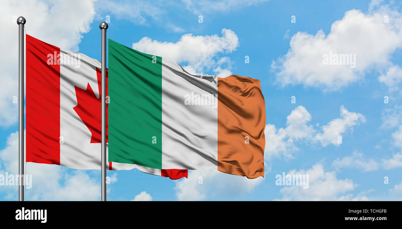 Canada and Ireland flag waving in the wind against white cloudy blue ...