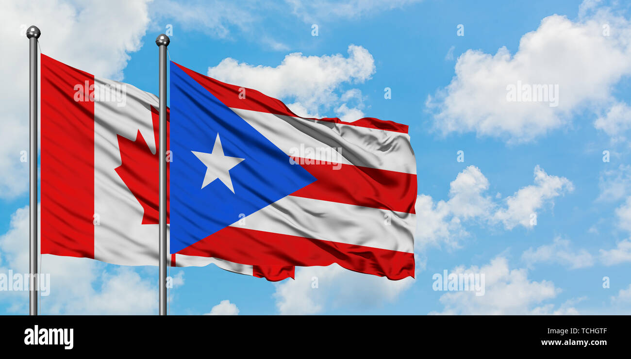 Canada and Puerto Rico flag waving in the wind against white cloudy ...
