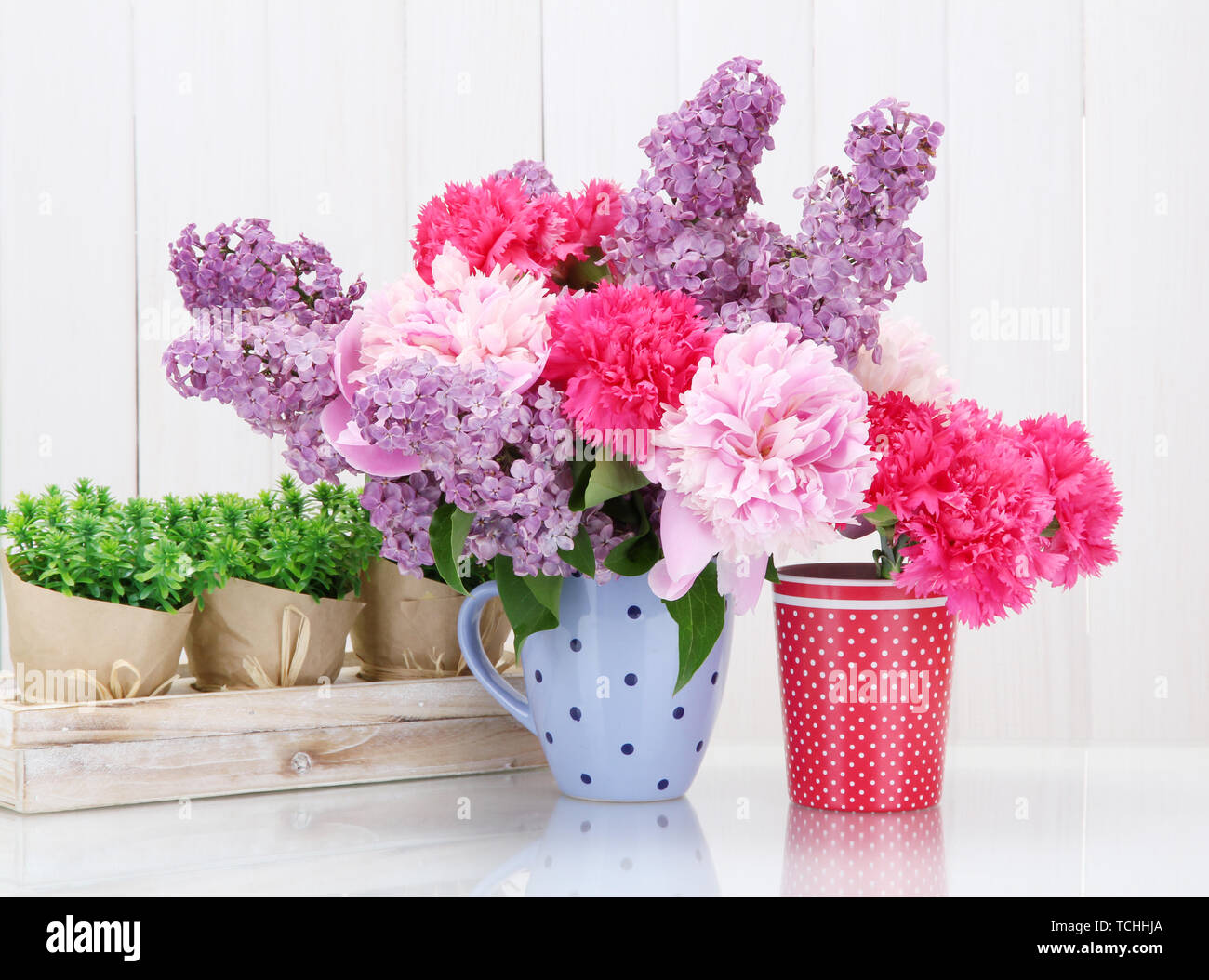 spring flowers in cups on table on white wooden background Stock Photo ...