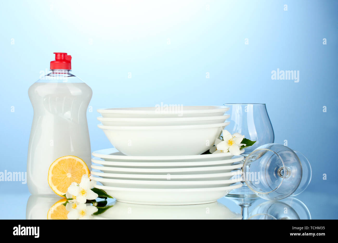 empty clean plates and glasses with dishwashing liquid and lemon on ...