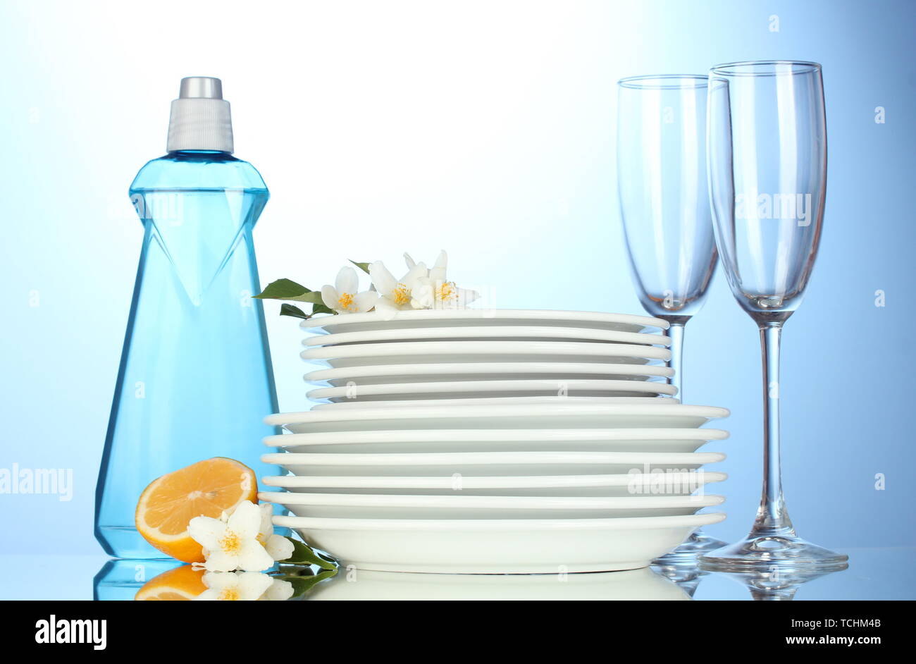 empty clean plates and glasses with dishwashing liquid, sponges and ...