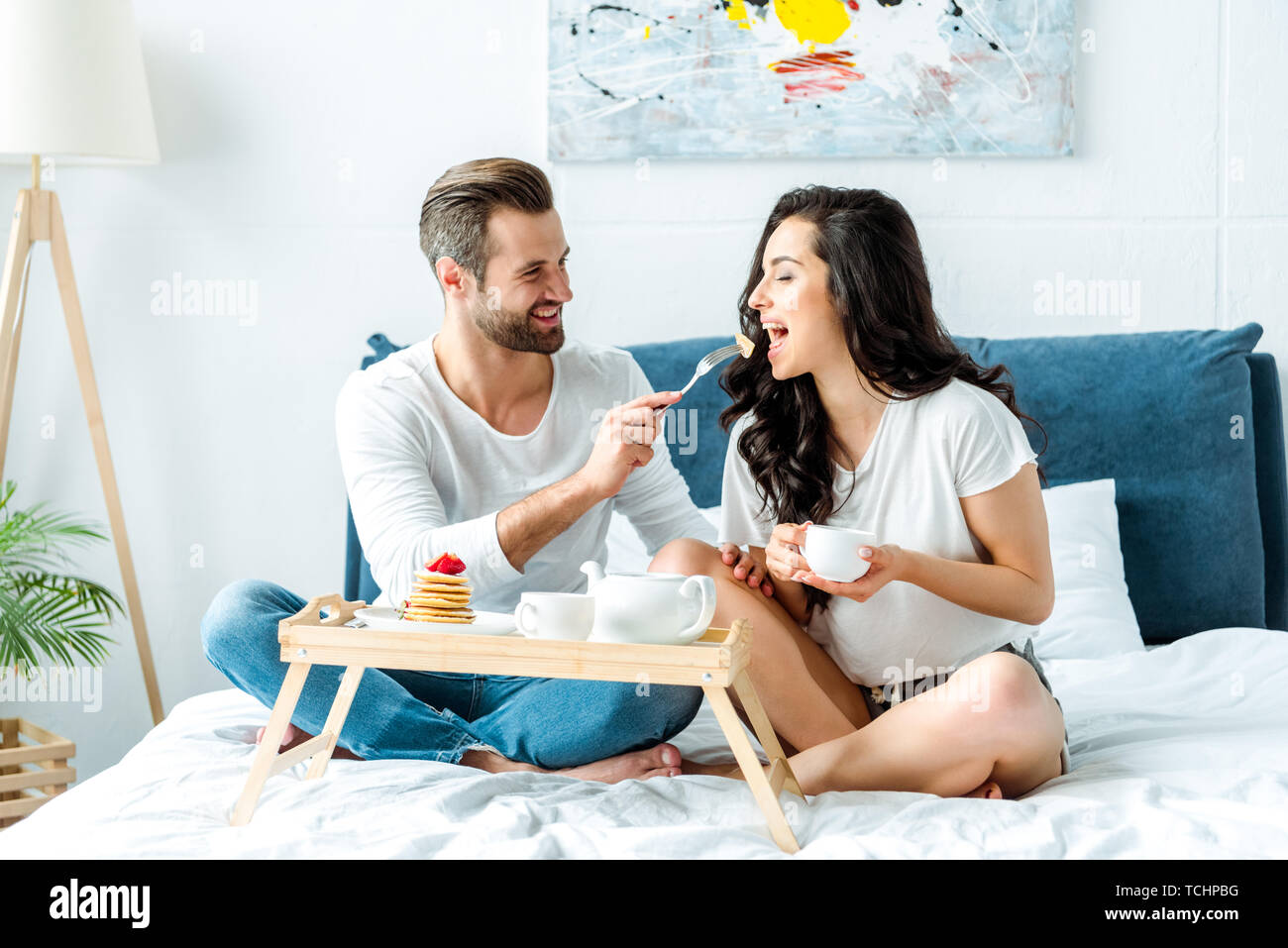 happy man feeding woman with cup in bed at morning Stock Photo - Alamy