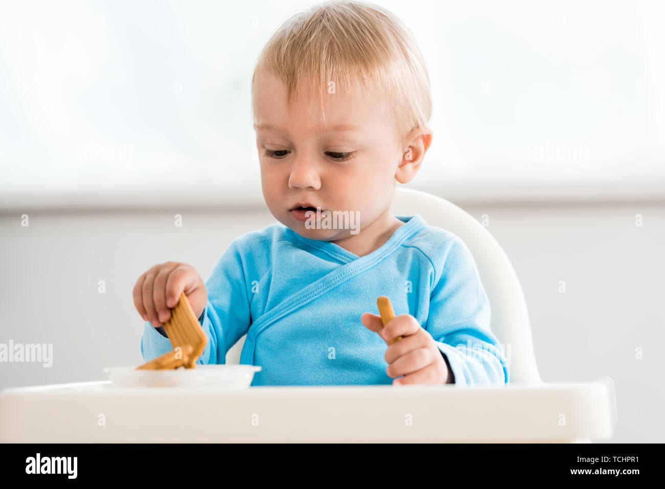 cute toddler kid sitting in feeding chair near tasty cookies at home ...