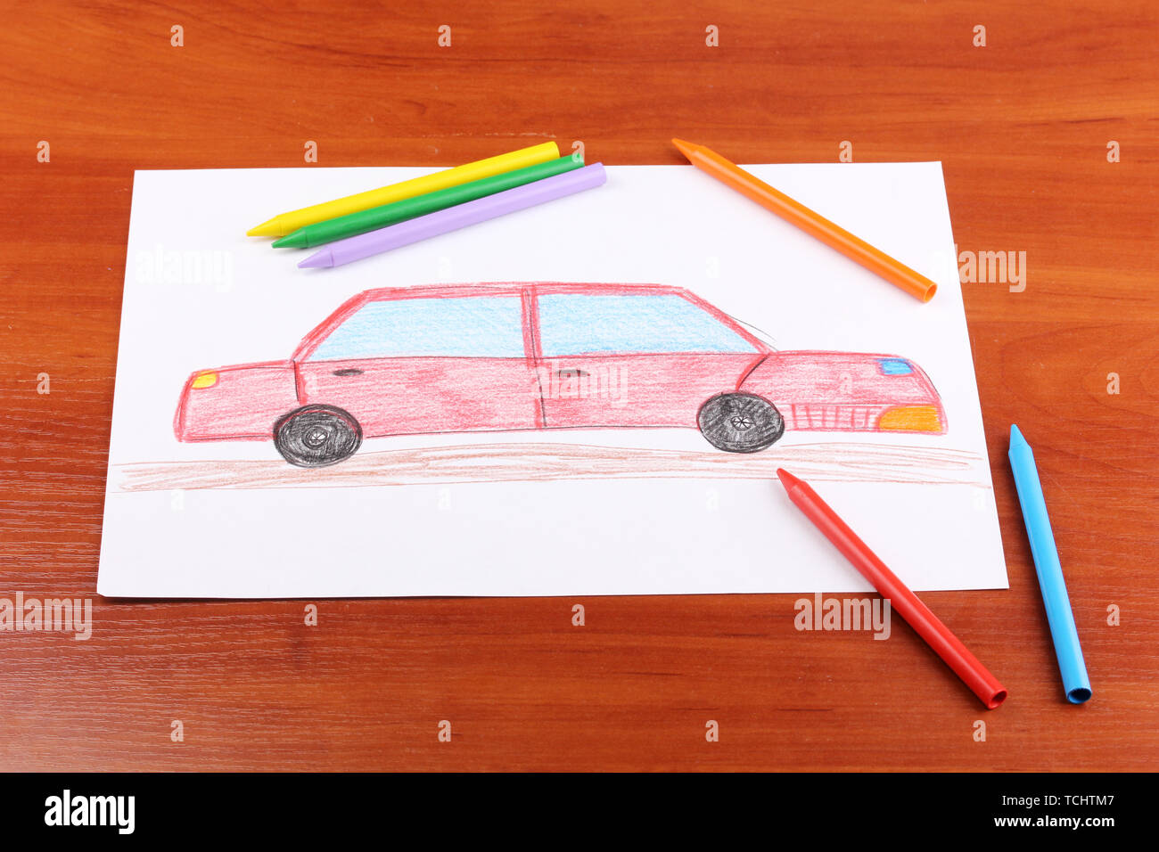 Children's drawing of red car and pencils on wooden background Stock ...