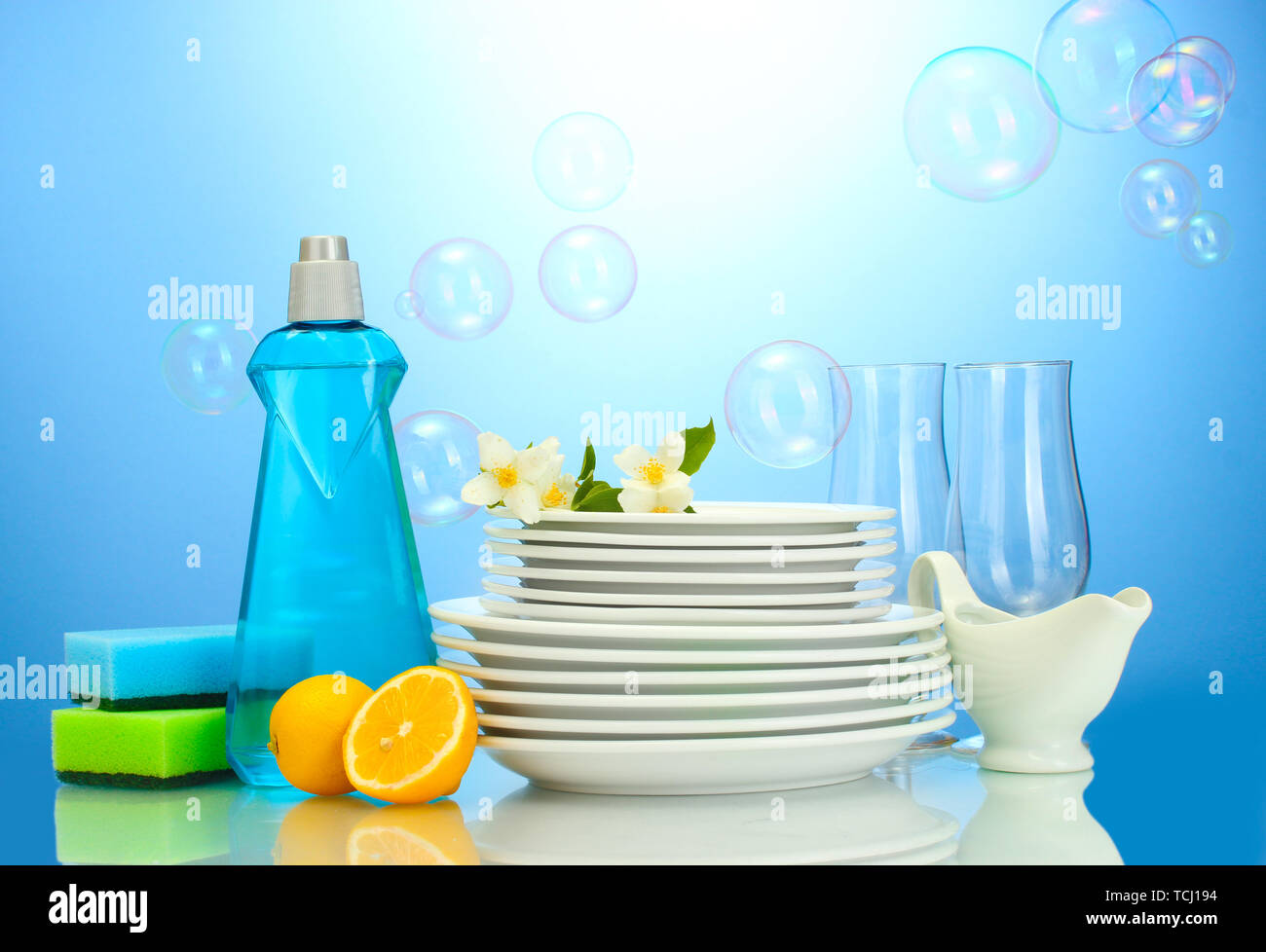 empty clean plates and glasses with dishwashing liquid, sponges and ...