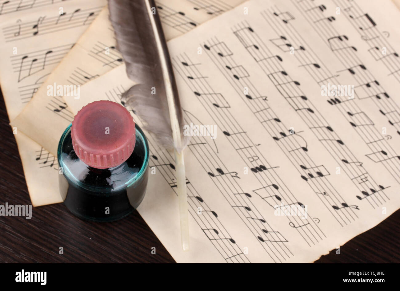 Musical notes and feather on wooden table Stock Photo - Alamy