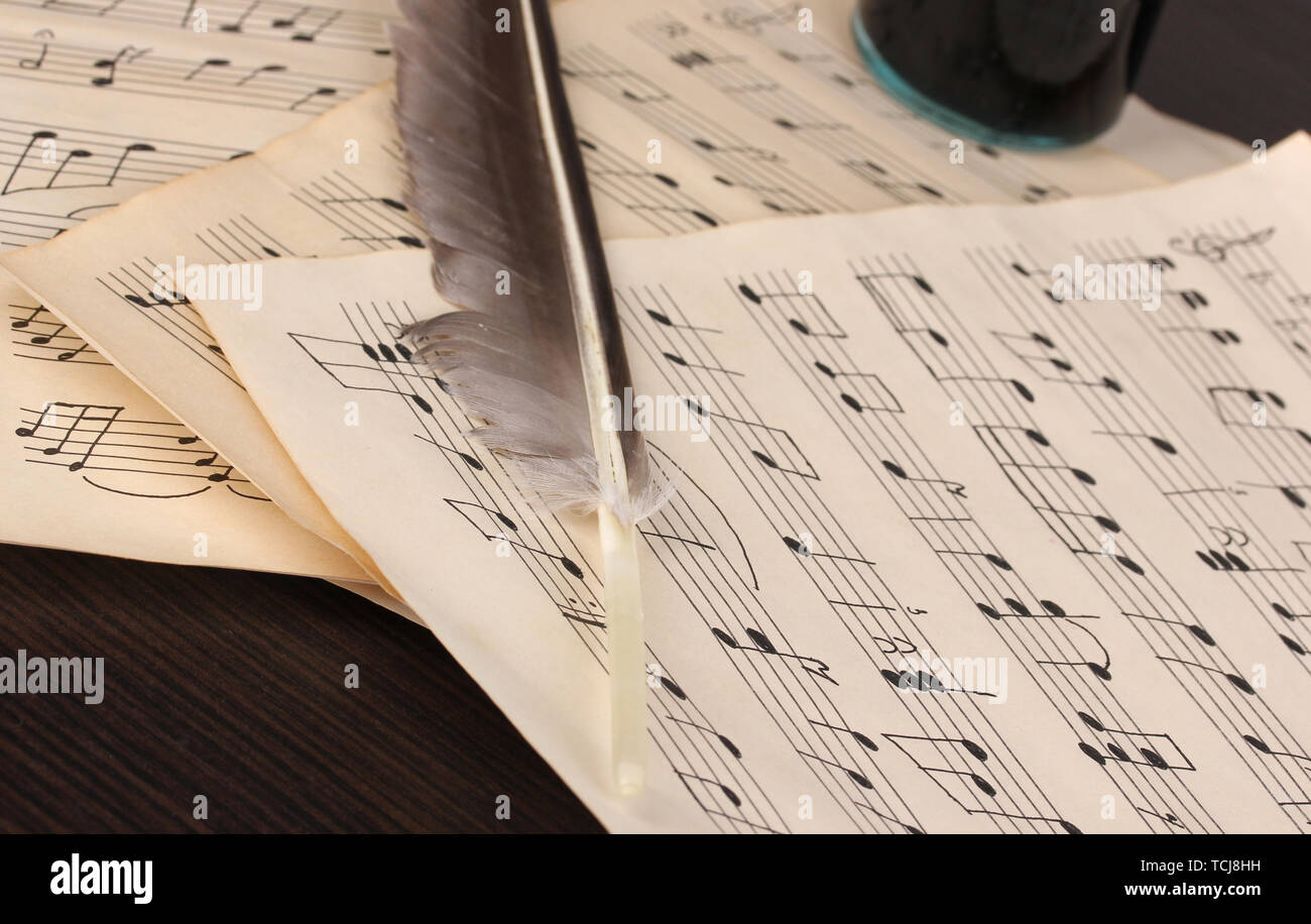 Musical notes and feather on wooden table Stock Photo - Alamy
