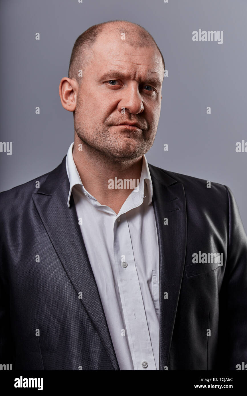 Serious angry man in suit looking. Portrait of actor on grey background ...