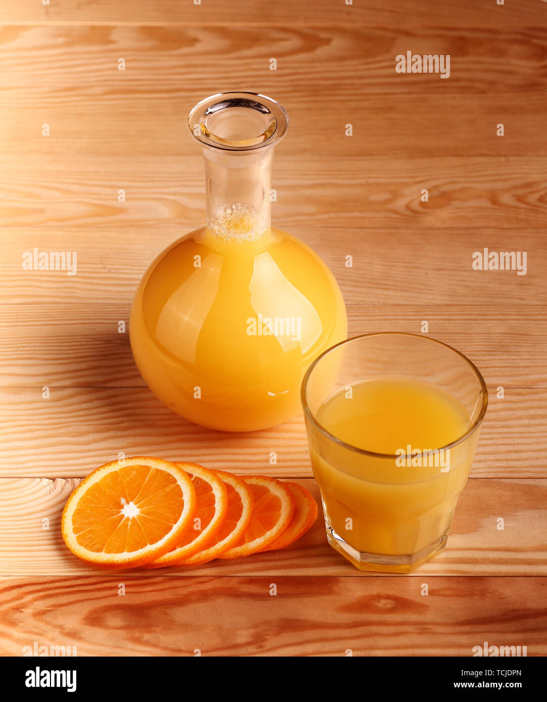 Glass of freshly pressed orange juice with sliced orange half on wooden ...