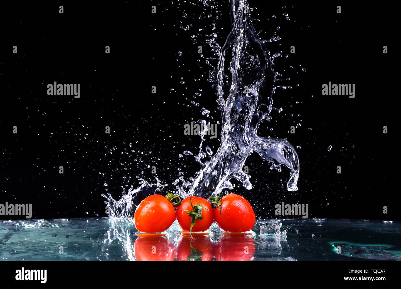 Studio shot with freeze motion of cherry tomatoes in water splash on ...
