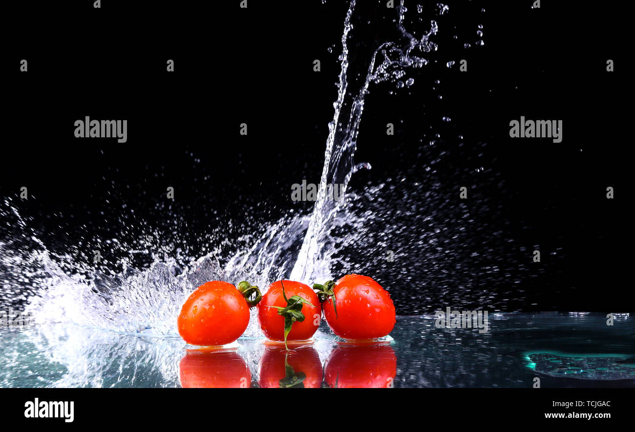 Studio shot with freeze motion of cherry tomatoes in water splash on ...