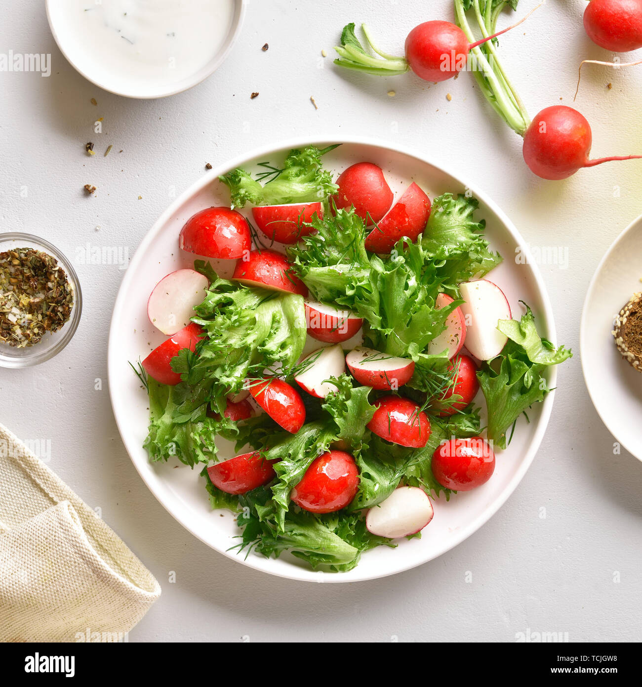 Close up of radish salad with lettuce leaves on platel over white stone ...