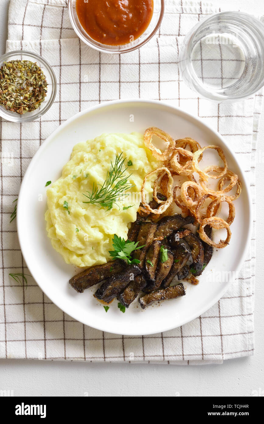 Fried beef liver with mashed potatoes and fried onion rings on white ...