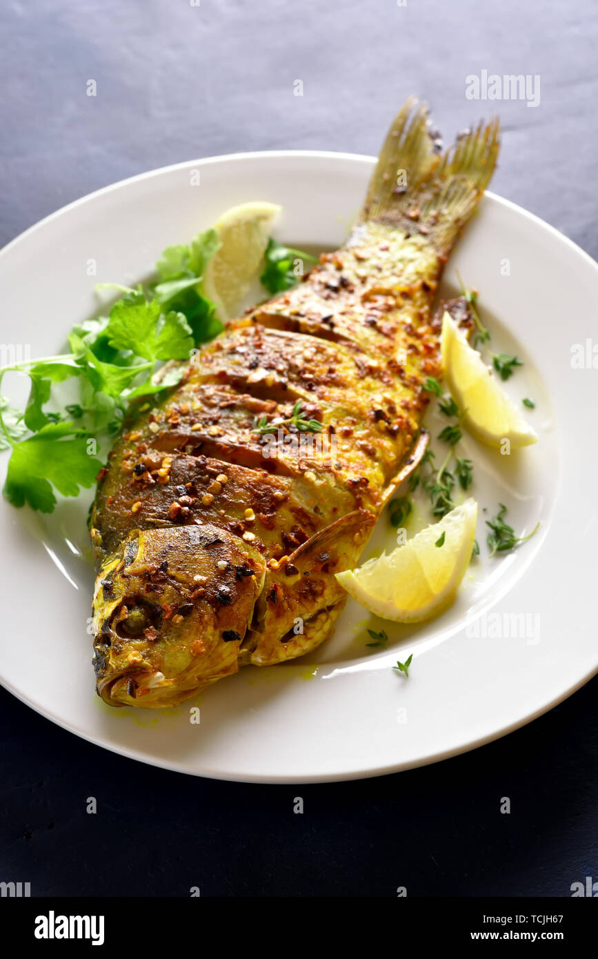 Grilled fish on plate over blue stone background Stock Photo - Alamy