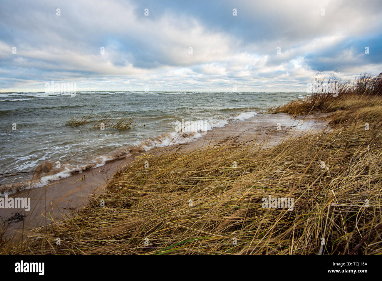 windy sea beach with white sand and blue water and dramatic clouds in the sky Stock Photo - Alamy