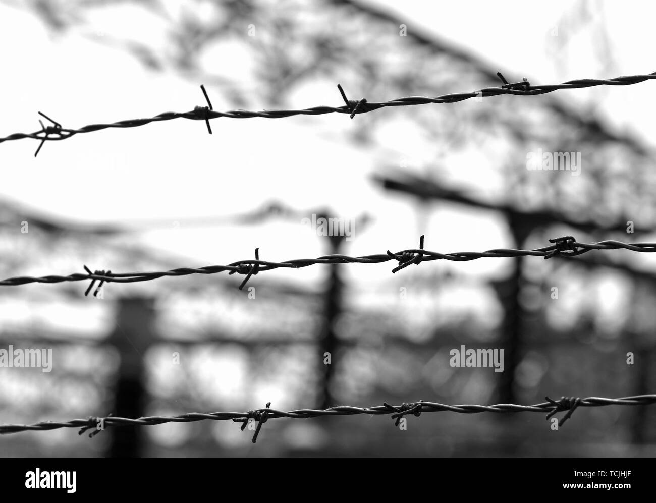 black and white background of barbed wire fence and blurred shapes ...
