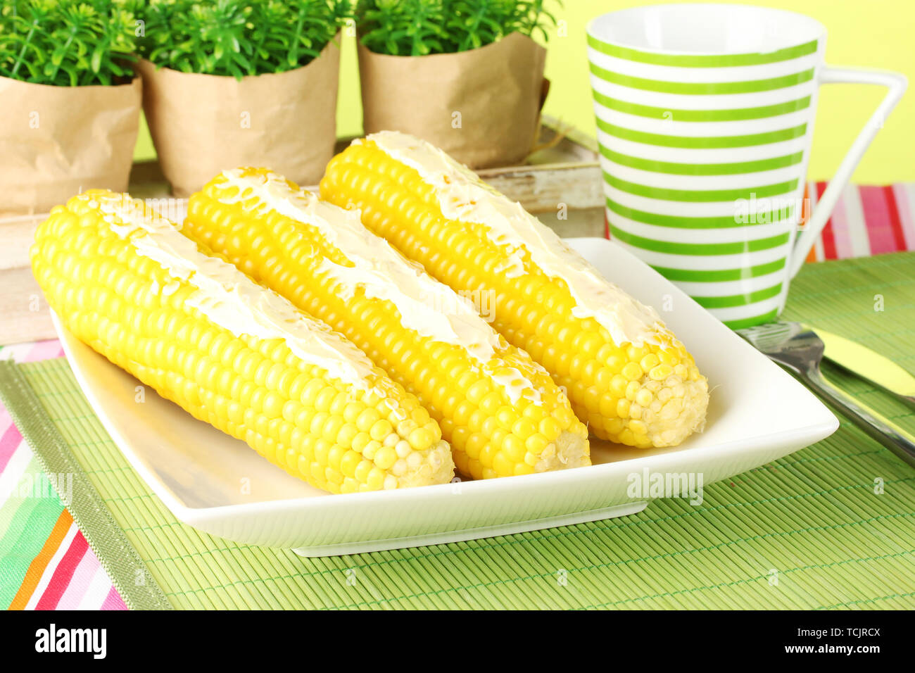boiled corn with butter on a green background Stock Photo - Alamy