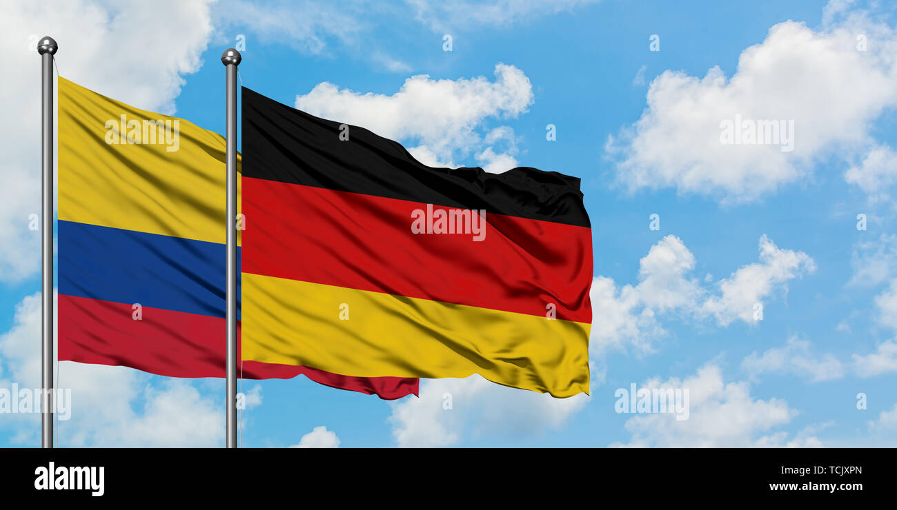 Colombia and Germany flag waving in the wind against white cloudy blue ...