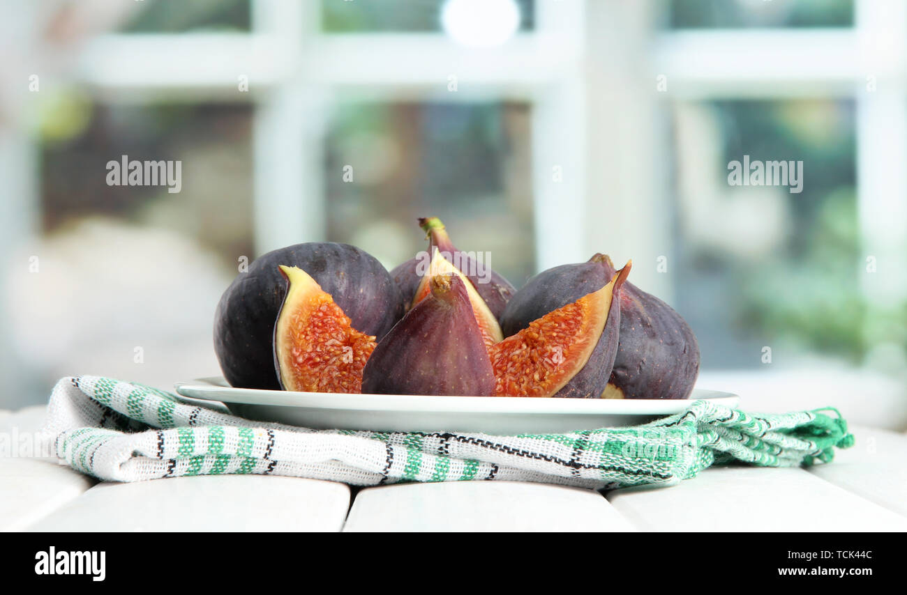 Ripe sweet figs on plate, on wooden table, on window background Stock ...