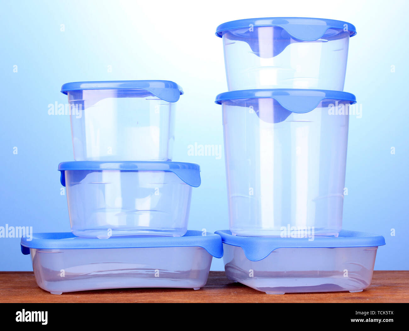 Plastic containers for food on wooden table on blue background Stock ...