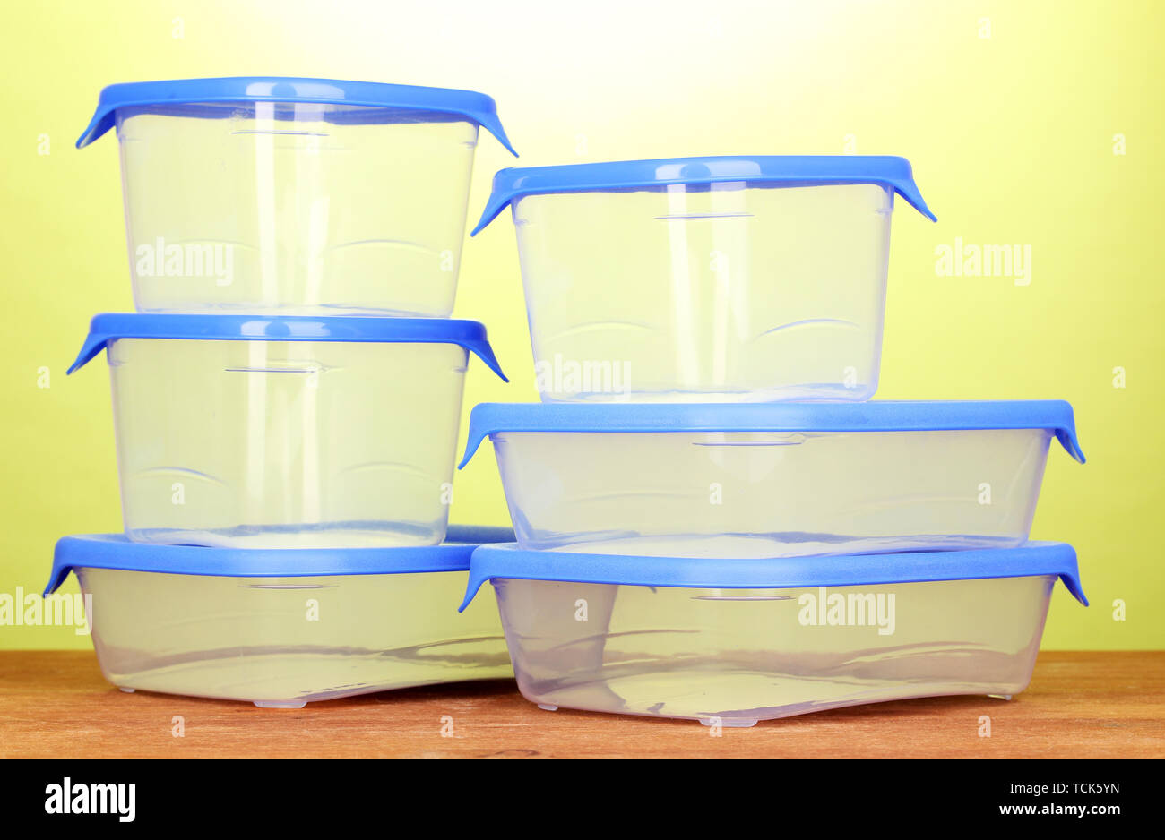 Plastic containers for food on wooden table on green background Stock ...