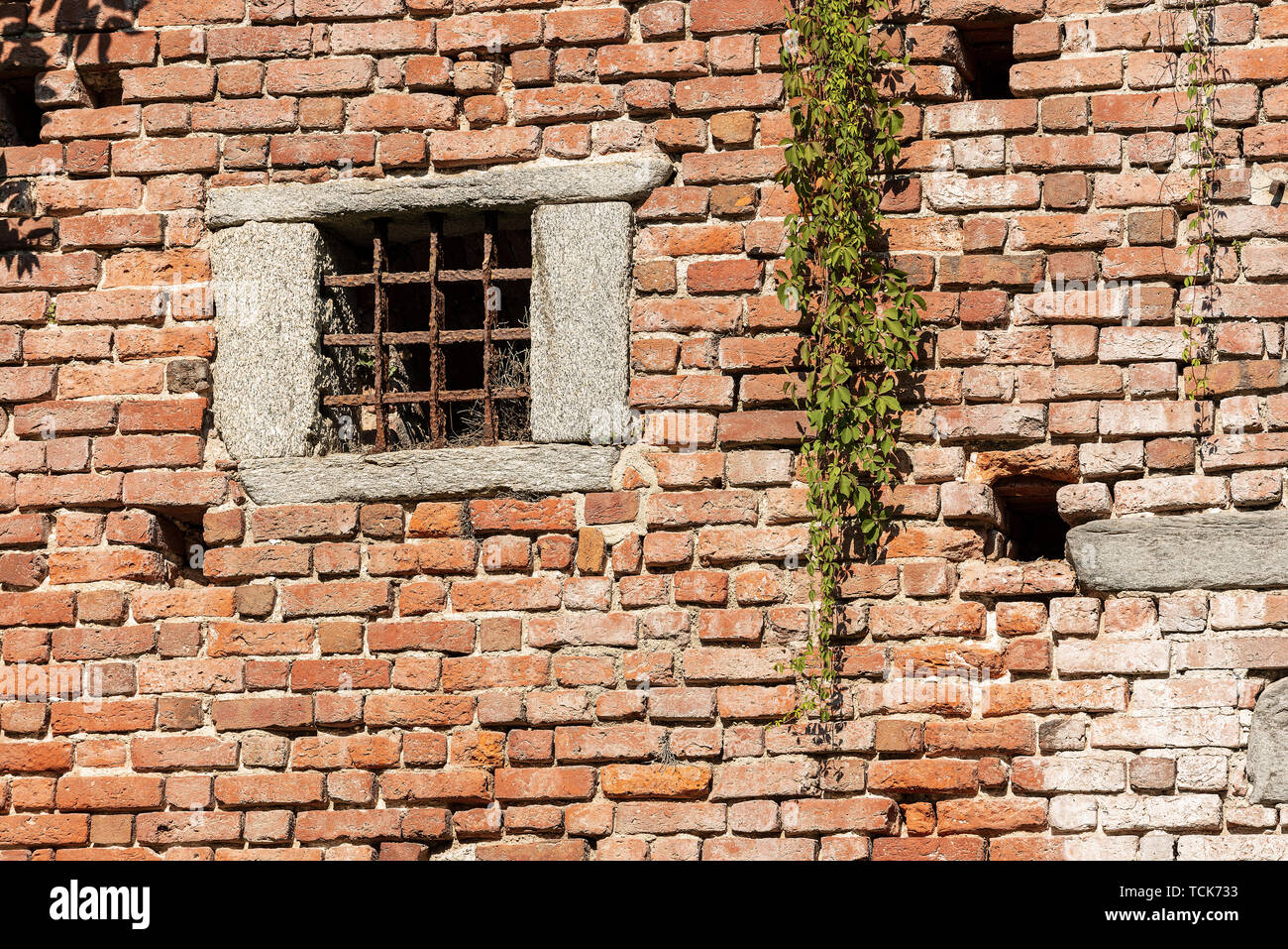 Detail of a medieval brick wall with a window with wrought iron bars ...