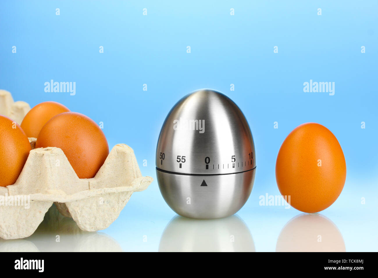 eggs in box and egg timer on blue background Stock Photo - Alamy
