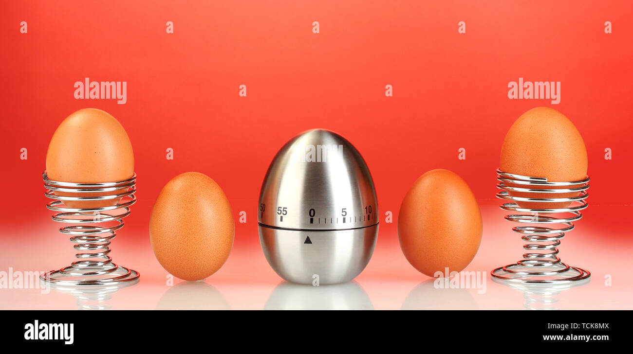 egg timer and eggs on red background Stock Photo - Alamy