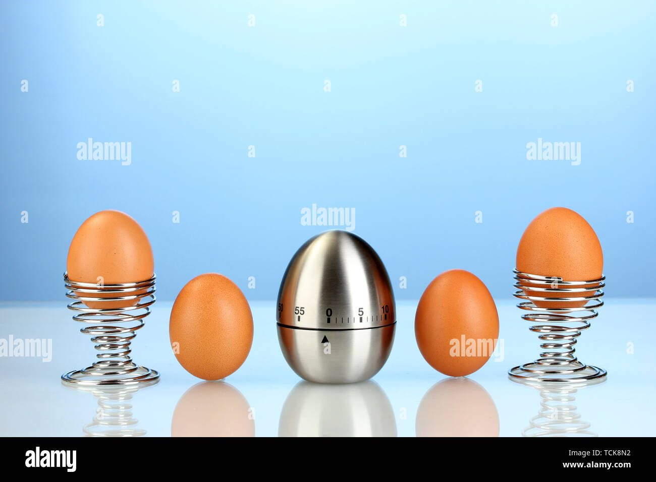 egg timer and eggs on blue background Stock Photo - Alamy
