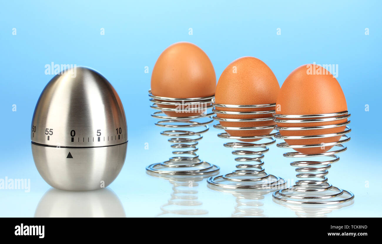 egg timer and egg in metal stand on blue background Stock Photo - Alamy