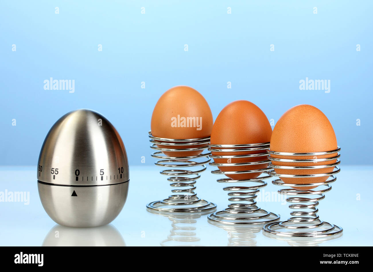 egg timer and egg in metal stand on blue background Stock Photo - Alamy