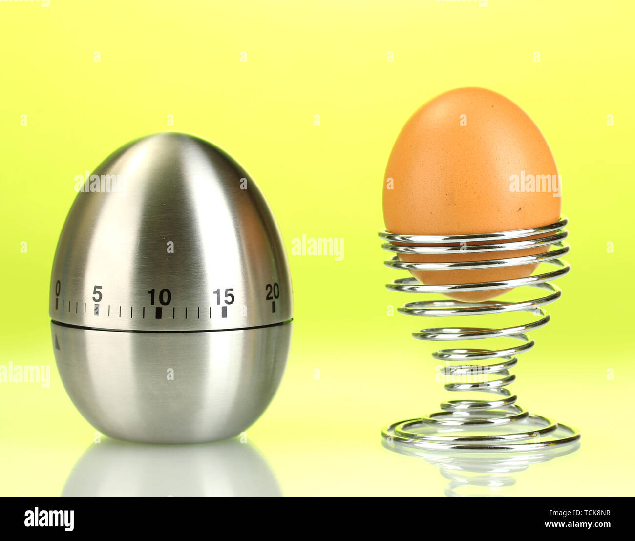 egg timer and egg in metal stand on green background Stock Photo - Alamy