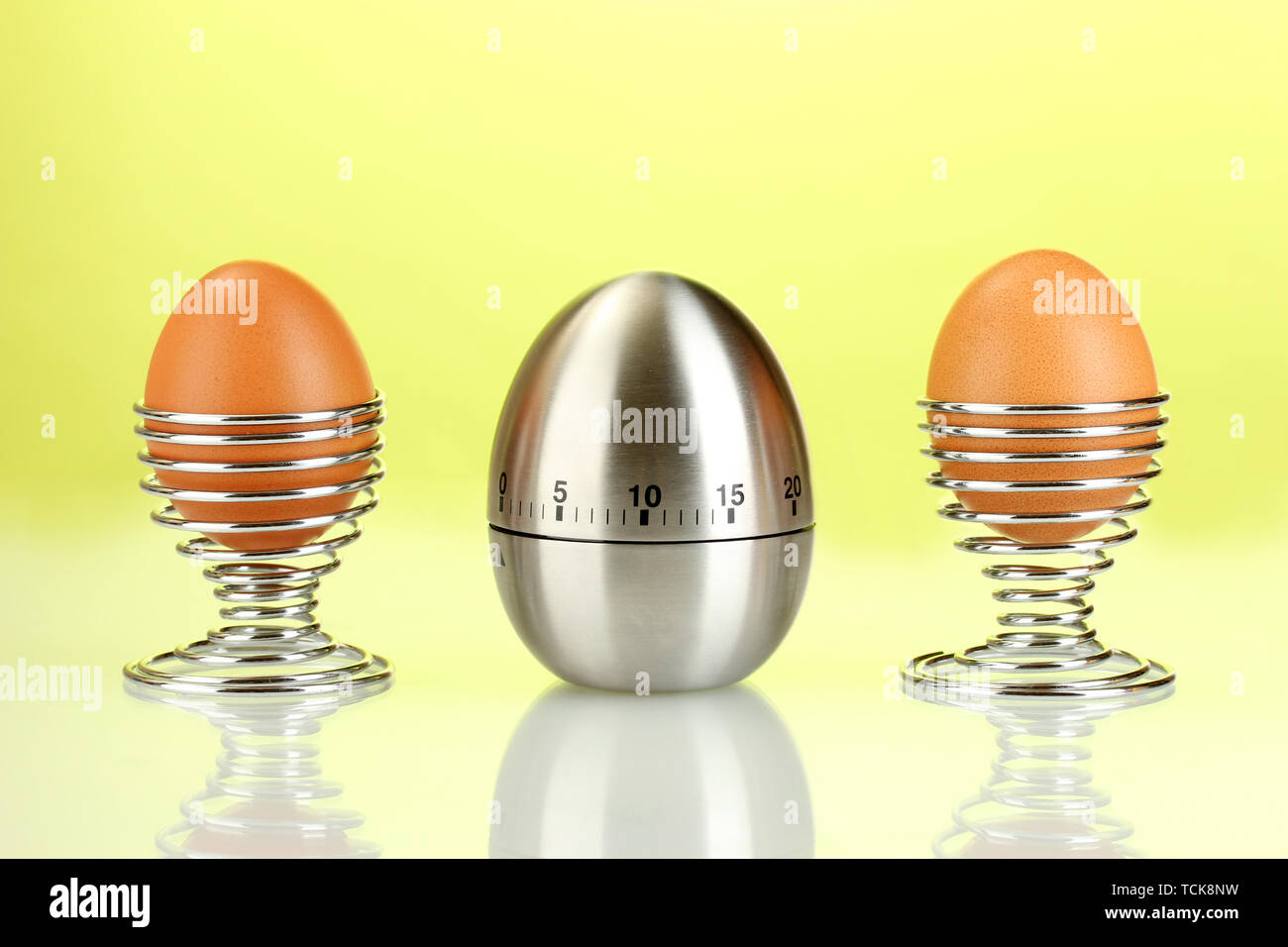 egg timer and egg in metal stand on green background Stock Photo - Alamy