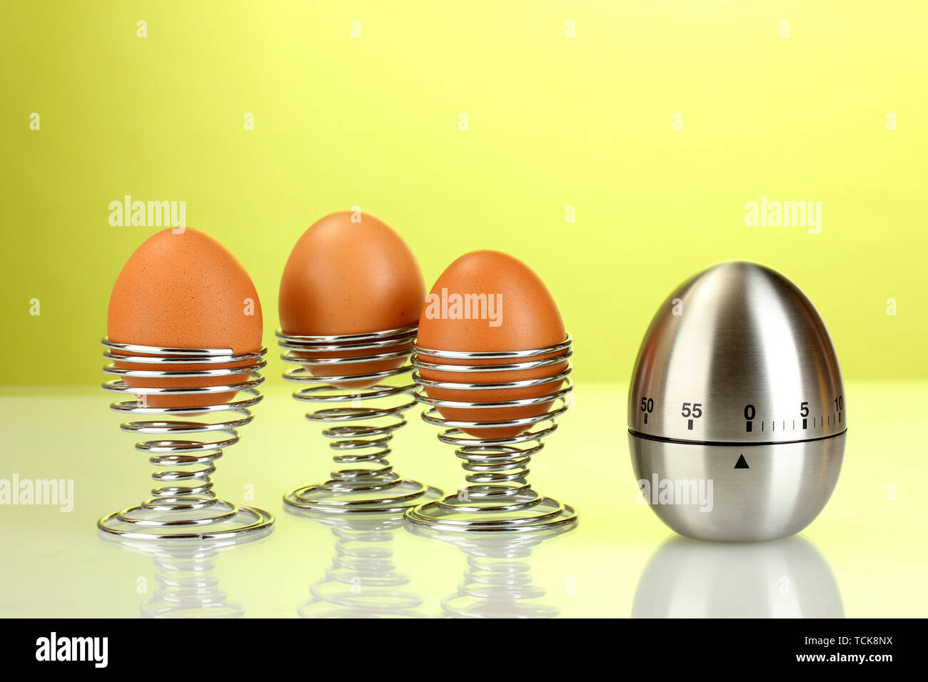egg timer and egg in metal stand on green background Stock Photo - Alamy